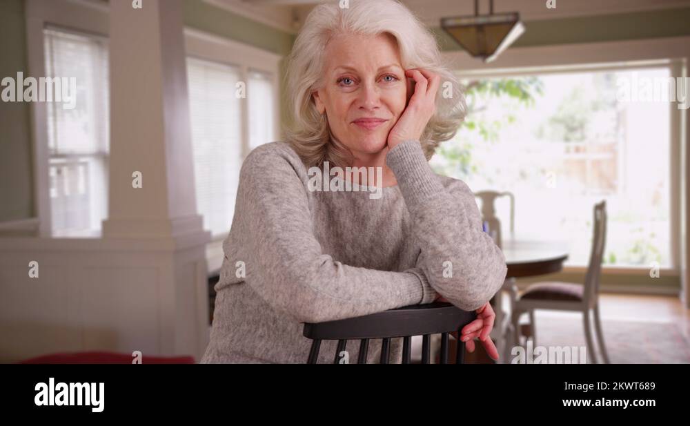 Portrait of lovely elder woman sitting in chair smiling at camera ...
