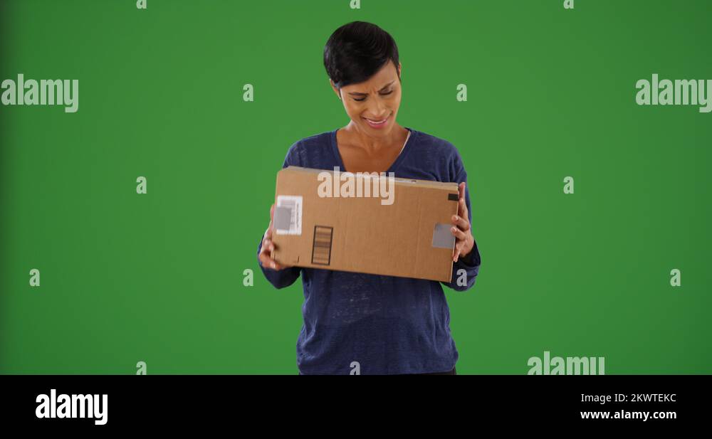 Female shaking cardboard box excitedly, guessing what's inside on green ...