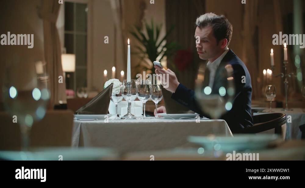 a lonely young man in the restaurant with a smartphone waiting for a ...