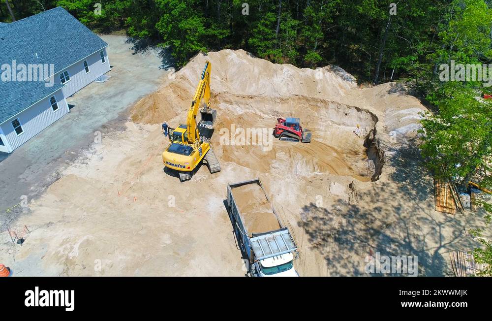 Pull Away Shot of Excavator, Dump Truck and Track Loader Digging a Fou ...