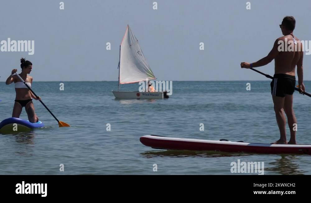 Young people couple stand up paddle boarding and surfing popular water ...