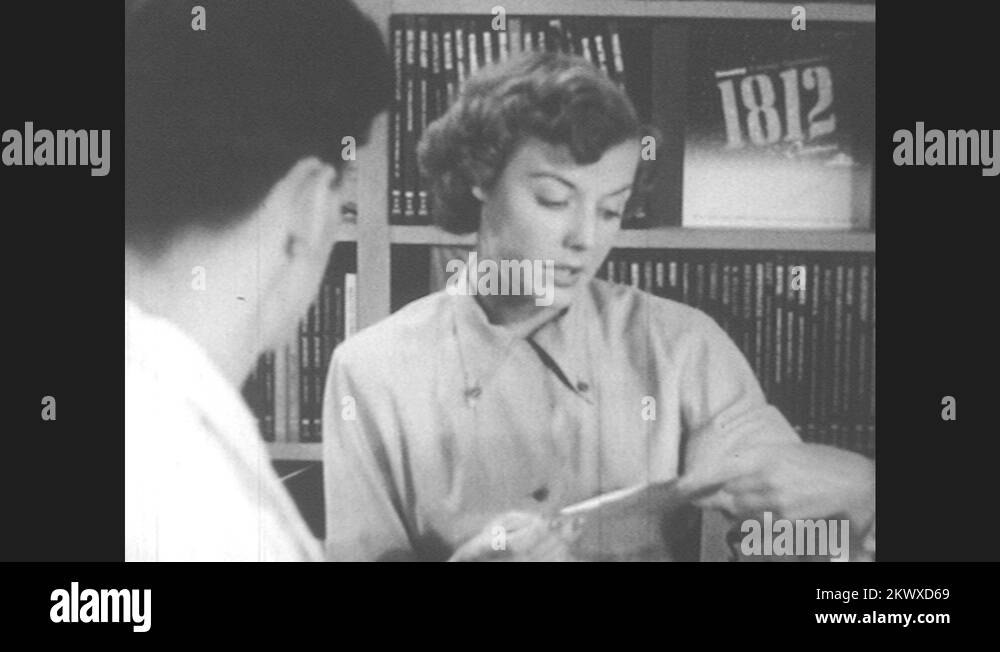 1950s: Woman behind counter in record store hands teen boy paper. Woman ...