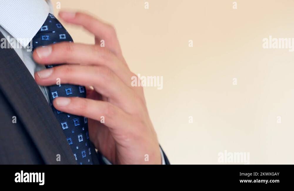 A business man takes off his black tie and unbuttoned the top button on ...
