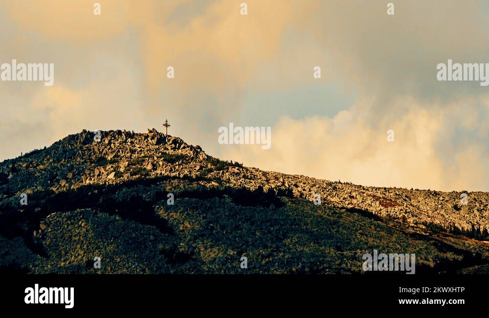 Clouds fly over a Christian cross on top of a stone hill. 4K time-lapse ...