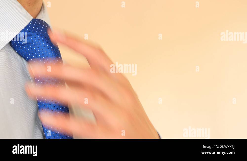 A business man takes off his blue tie and unbuttoned the top button on ...