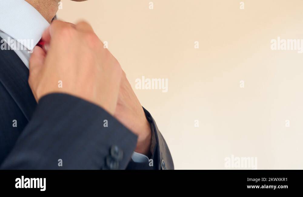 A business man takes off his red tie and unbuttoned the top button on ...