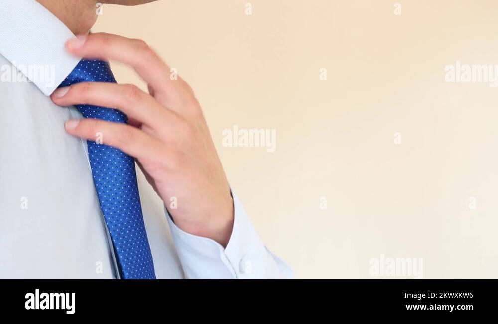 A business man takes off his blue tie and unbuttoned the top button on ...