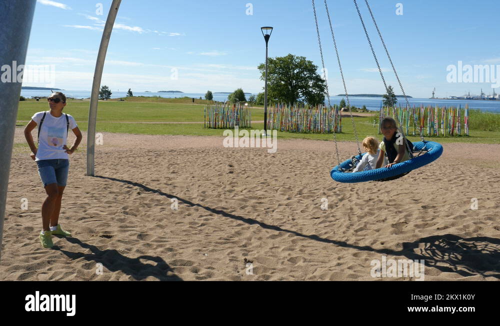 Mom with two childs walking in park and swinging on big swing set Stock ...