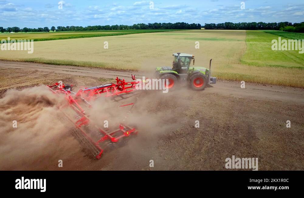 Farming tractor with trailer for plowing working on cultivated field ...
