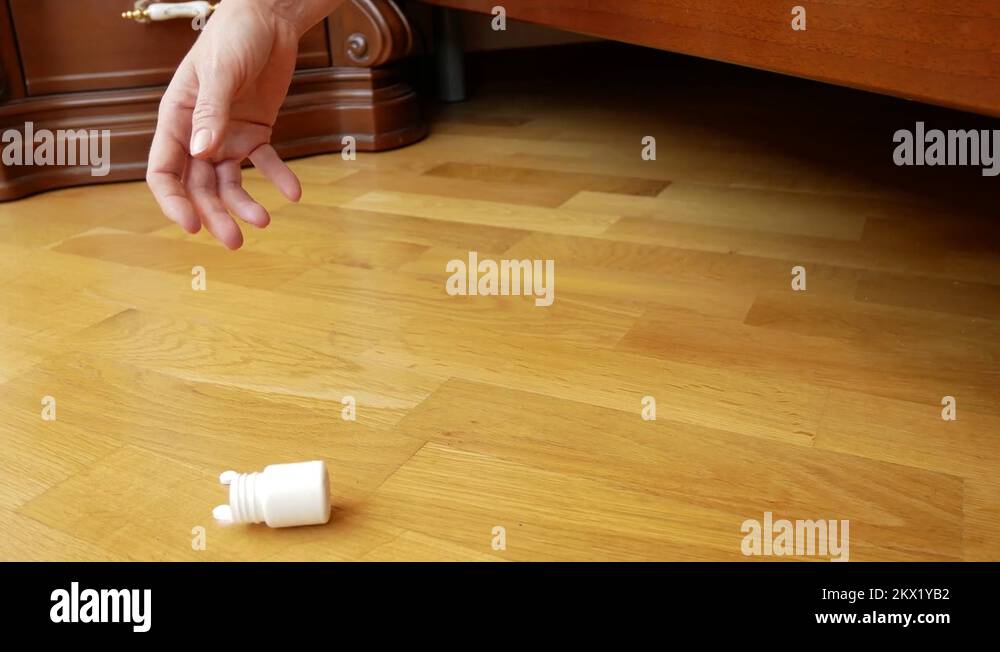 Close-up. Tablets fall out of the hand of a woman lying on the bed ...