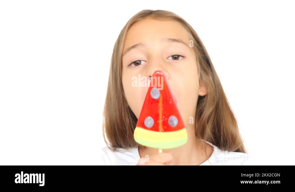 A little girl licks a lollipop in the form of a water-melon slice. 4k ...