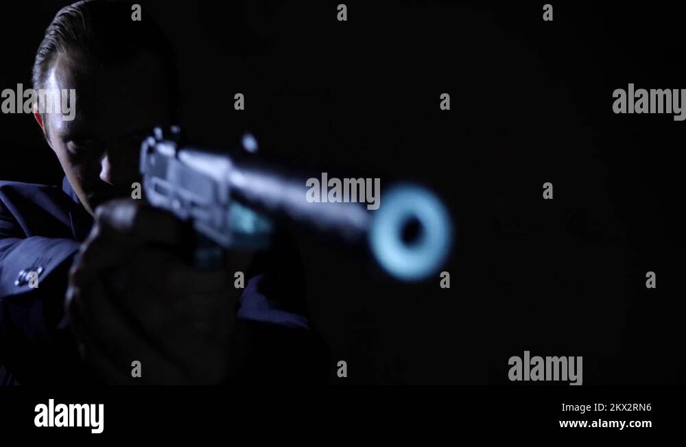 Man pulling out his gun in the darkness and aiming at the camera. 4k ...