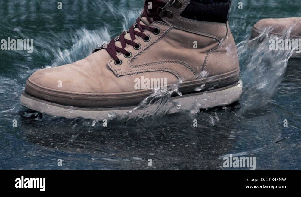 Man in Boots Step on a Puddle and Create a Splash in Slow Motion Stock ...