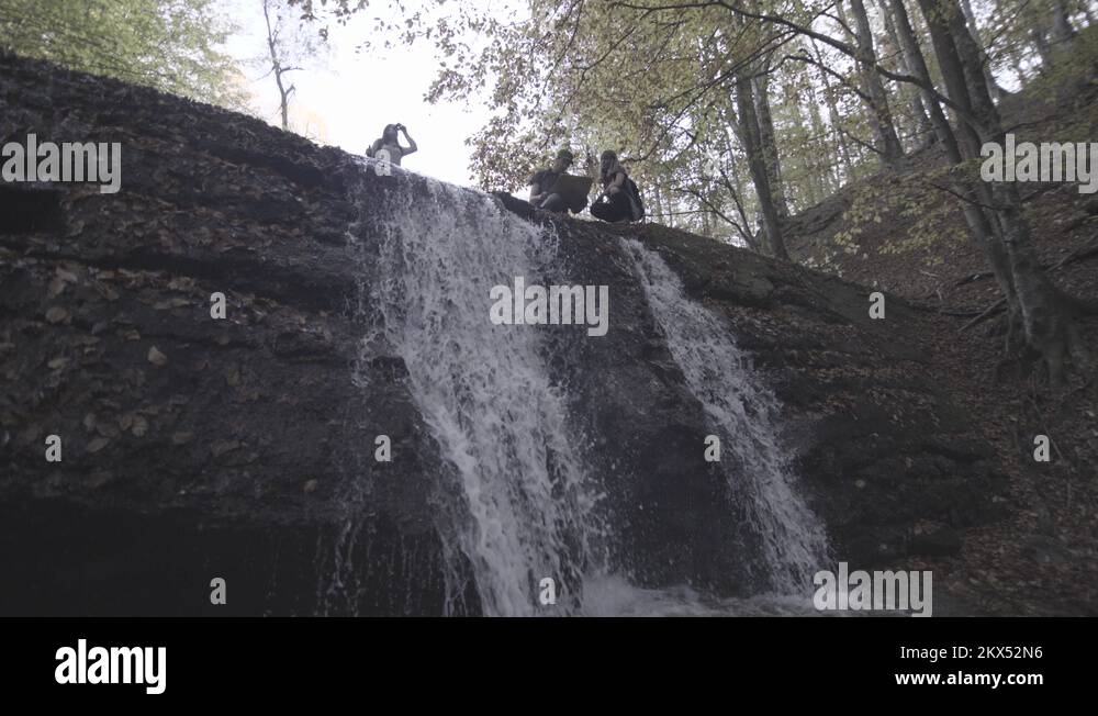 Hikers observing environment while standing on the top of waterfall in ...