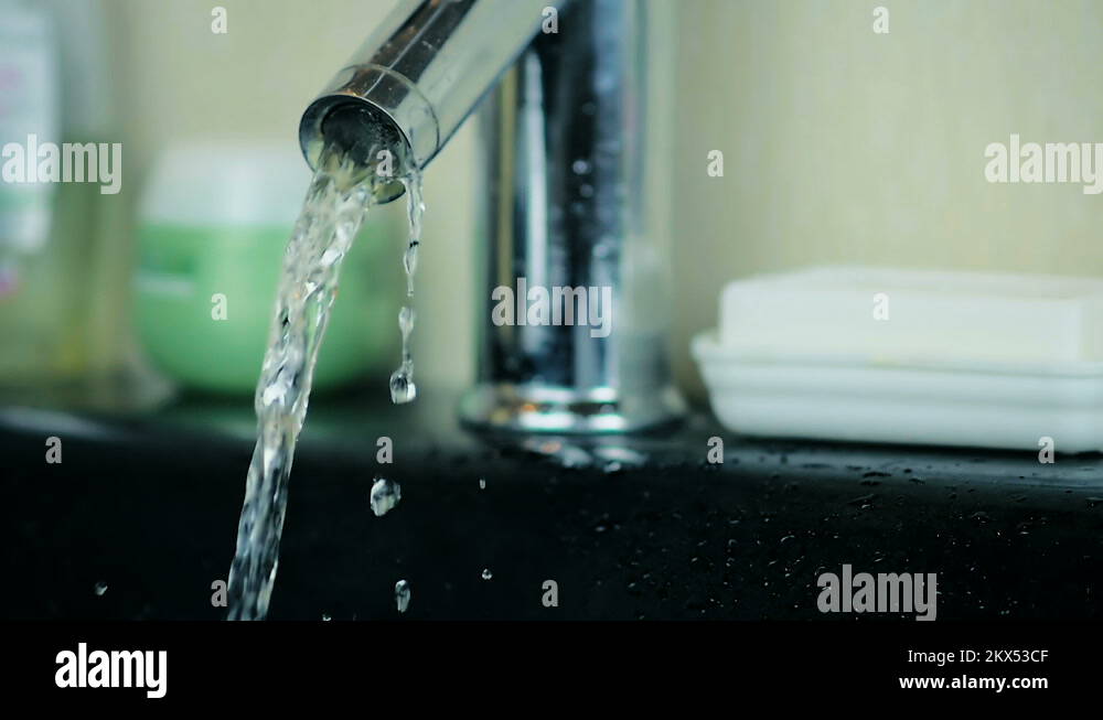 Powerful stream of water flowing from an aluminum tap in the bathroom ...