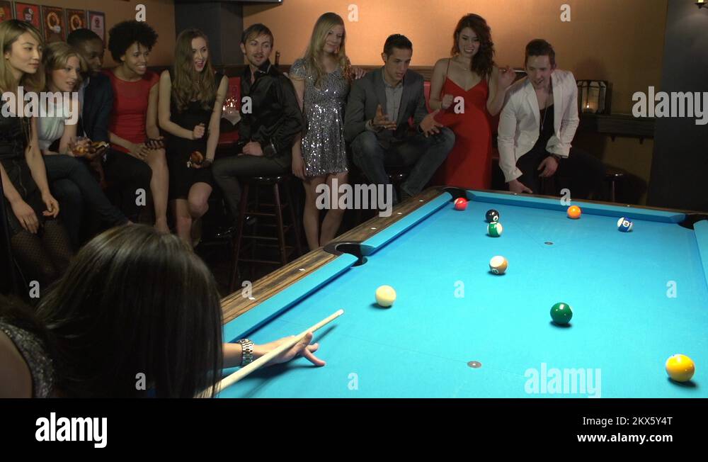 A diverse group of young and attractive friends playing pool at ...