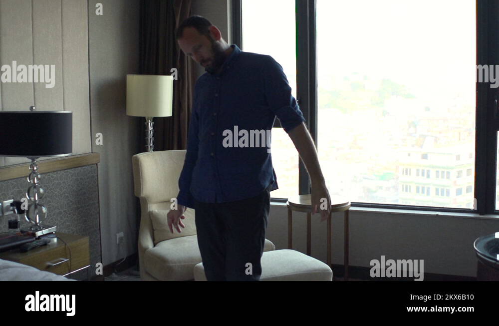 Drunk man drinking beer and falling on bed in bedroom at hotel, slow ...