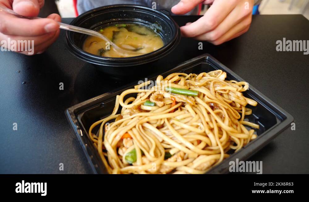 A man is eating Chinese food in a fast food restaurant. 4k. Slow motion ...