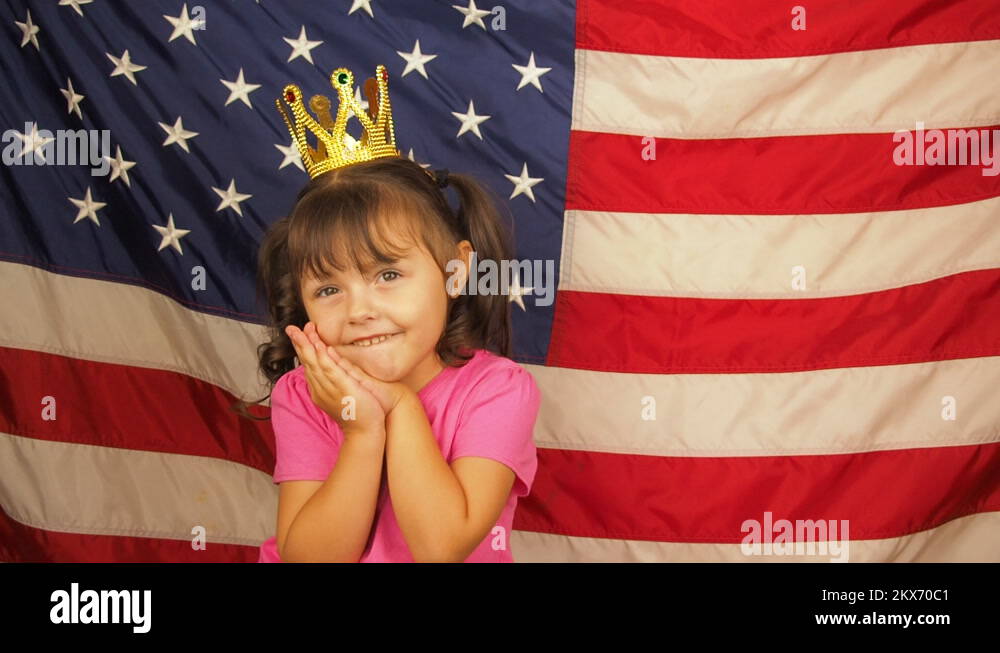 Beautiful little girl in the crown on the background of the US flag ...