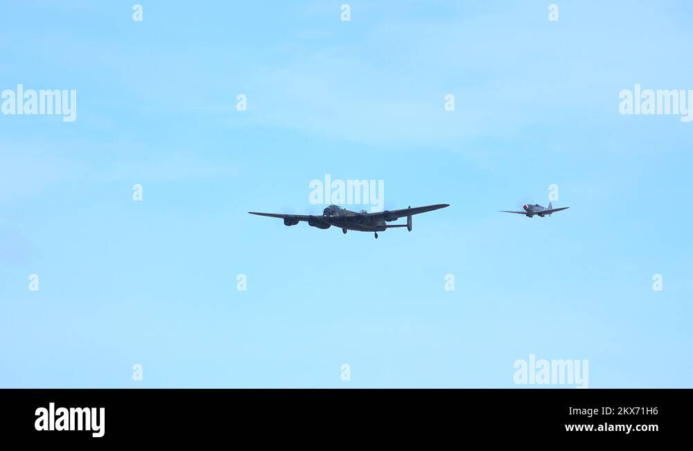 Lancaster bomber with spitfire or Hurricane flying in blue sky with ...