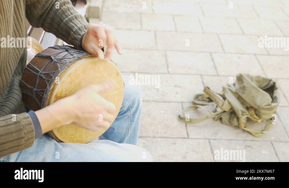 A street musician plays on an African drum. Man playing on a Bongo drum ...