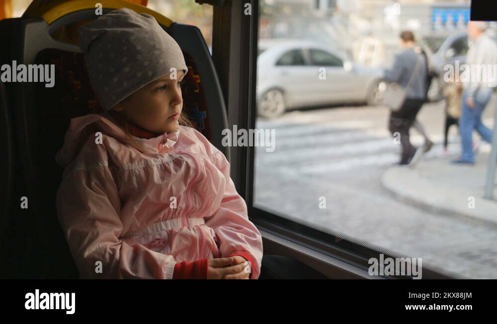 Little Blonde Girl in a pink jacket, Kid is Sitting in a Bus Cabin ...