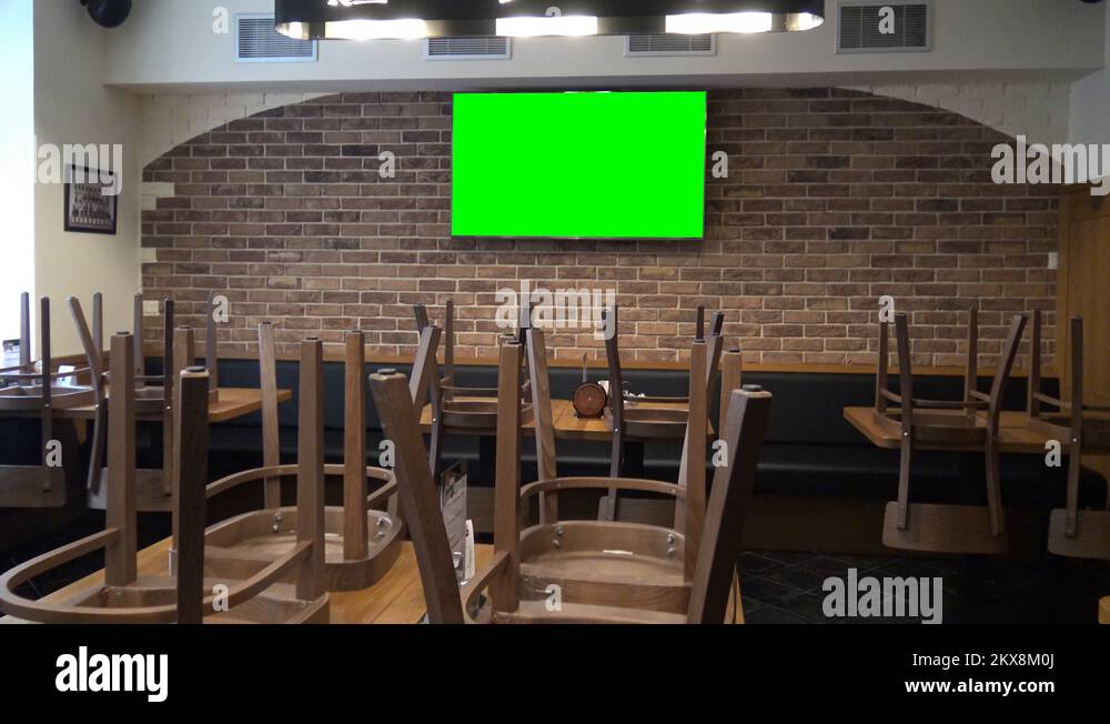 The interior of a bar with a TV green screen on a wall - chairs on ...