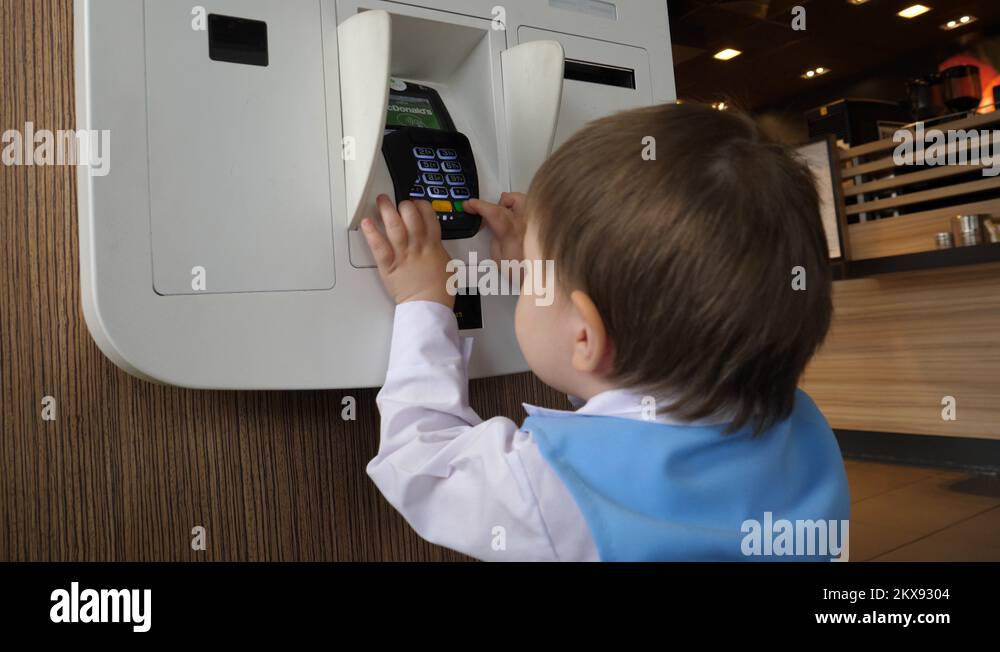 Child boy plays with the terminal buttons for payment card in fast food ...
