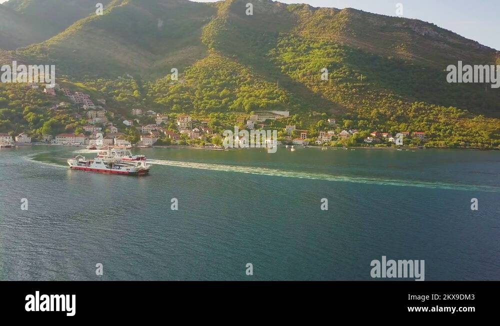 Ferryboats float between coastal towns at the shores of Kotor Bay ...