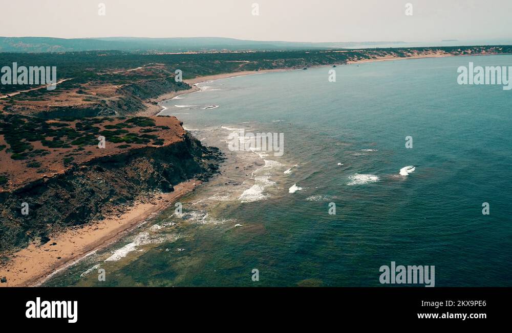 Drone view long coast line on wild sea beach. Sea water splash on rocky ...