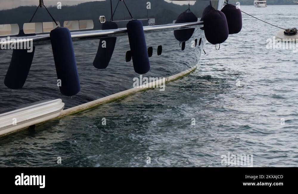 Mirror side of modern luxury boat reflects rippling water. Ship moored ...