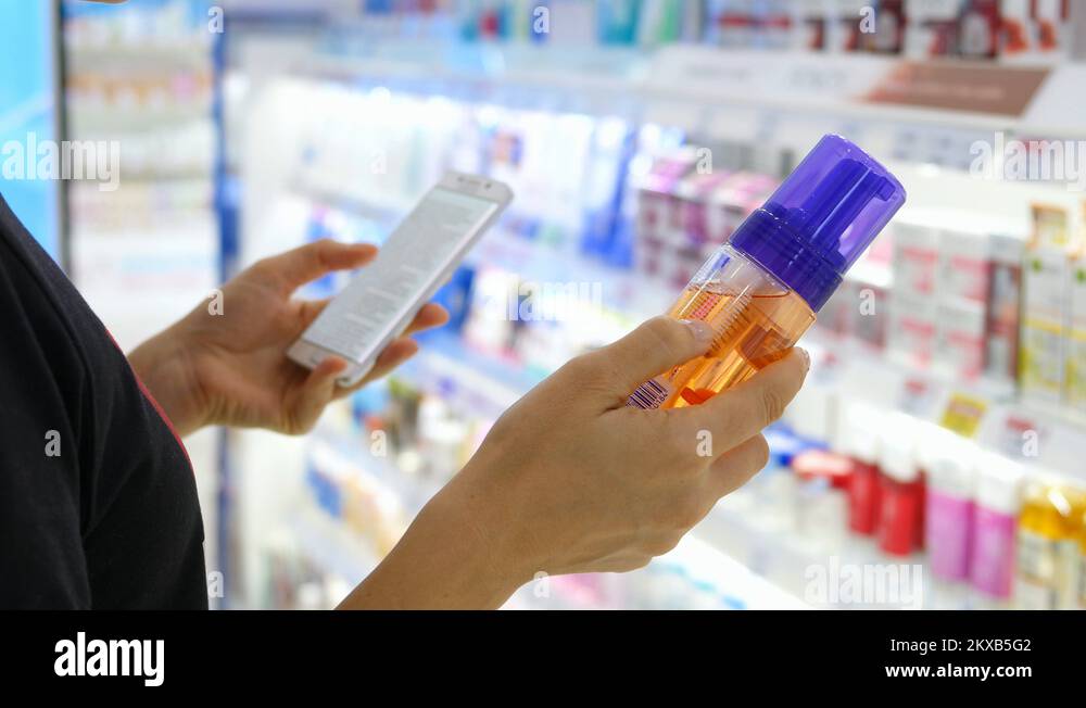 Woman Reading Product Label In Cosmetics Shop Using Mobile Phone Stock ...