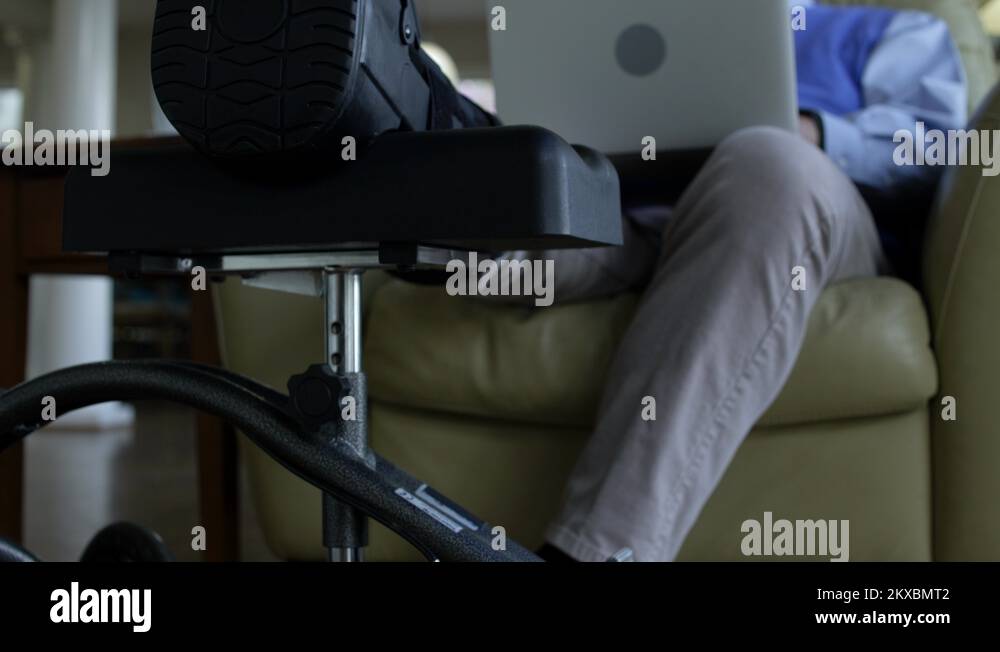 Senior man using a laptop at home with his broken leg propped up Stock ...