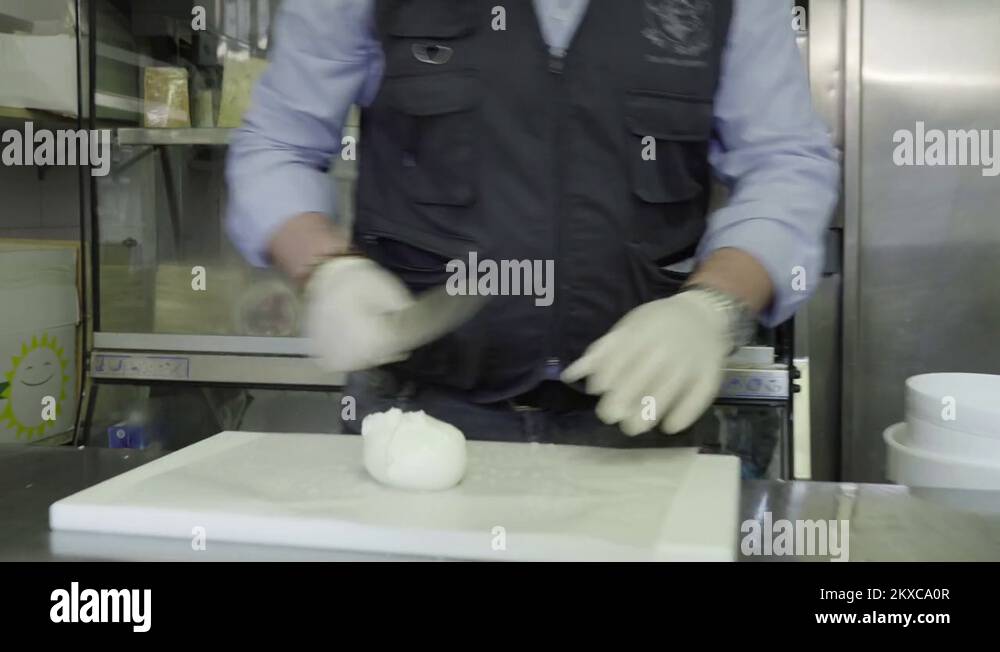 A man cuts a mozzarella in a traditional Italian dairy in Naples Stock ...