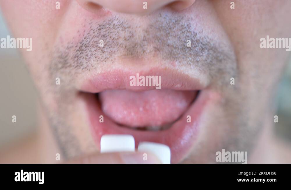 close-up, male mouth. the man puts the chewing gum in his mouth and ...