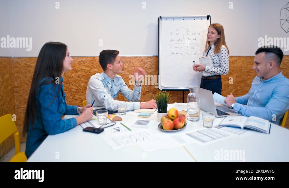 Lady is Explaining Theory to a Group of People near Flipchart in an ...