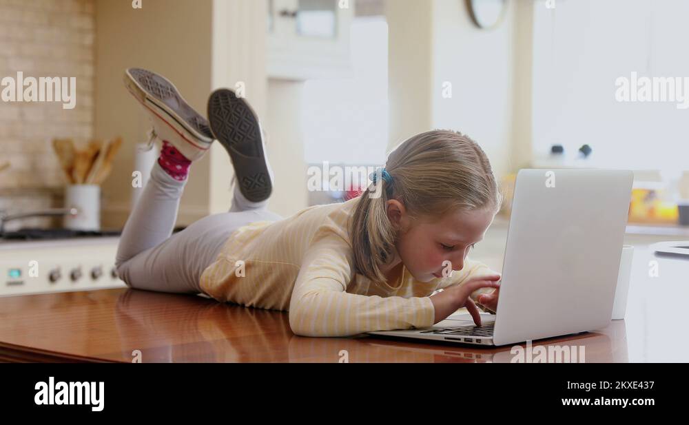 Happy little girl lying on table using her laptop 4K 4k Stock Video ...
