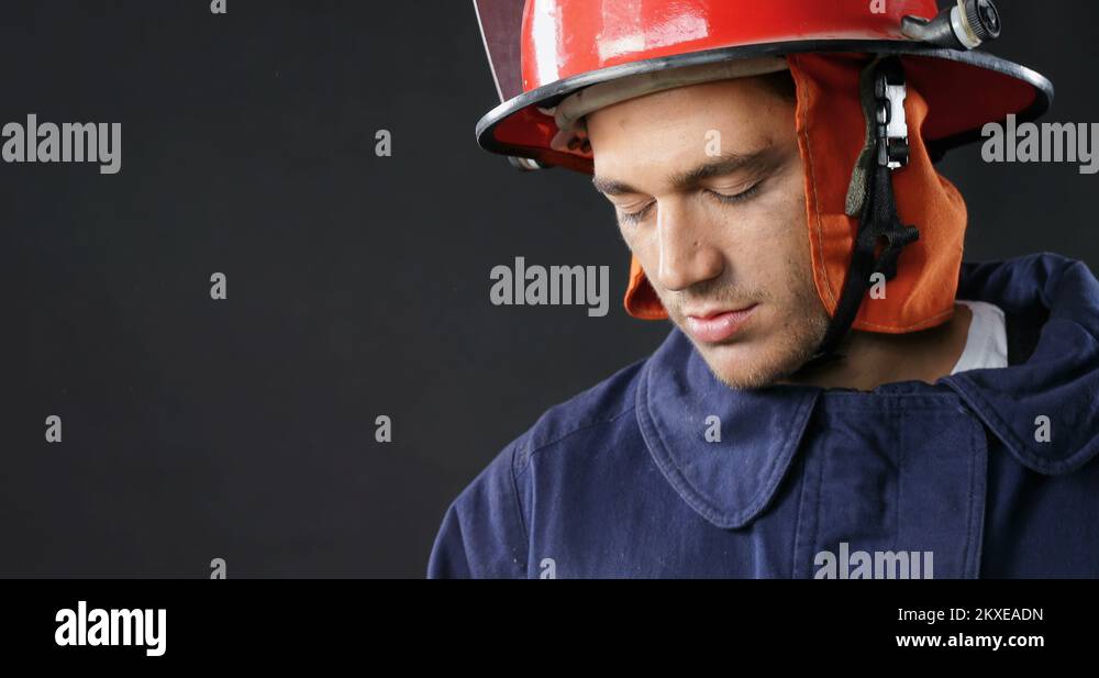 Thoughtful fireman standing against black background 4K 4k Stock Video ...
