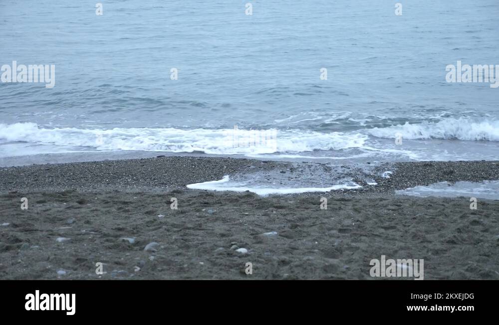Pebble beach at sunset. The waves splatter and break into droplets. 4k ...