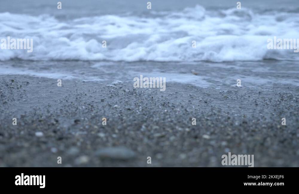 Pebble beach at sunset. The waves splatter and break into droplets. 4k ...