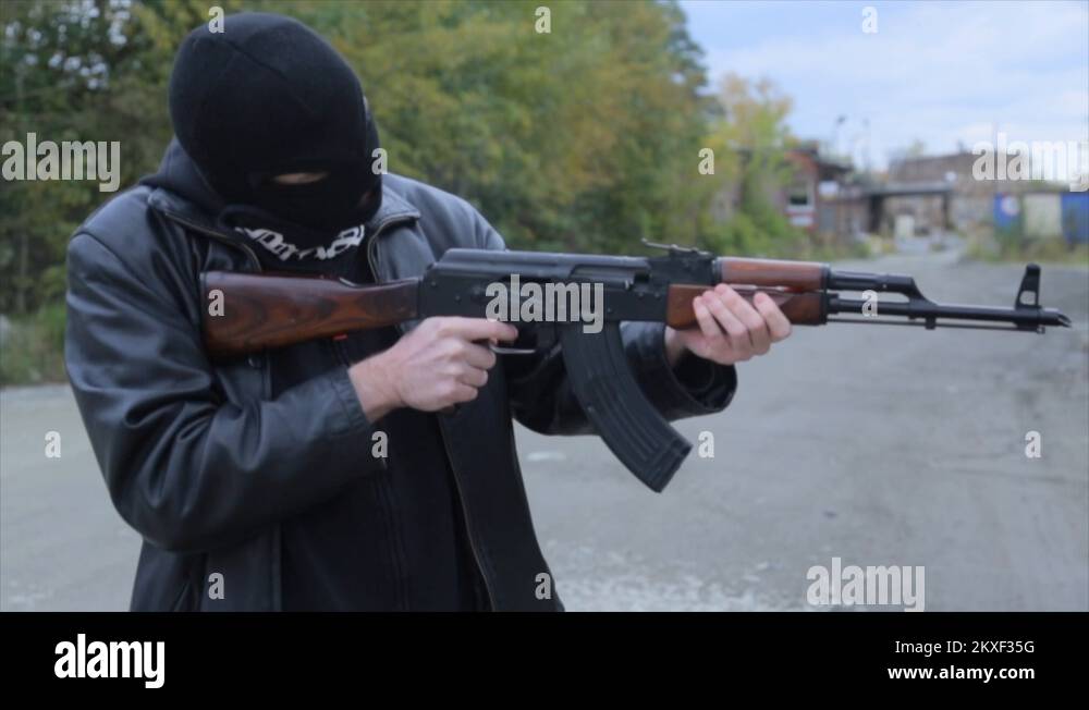 Armed man in black simulates shooting a machine gun. Bandit with ...
