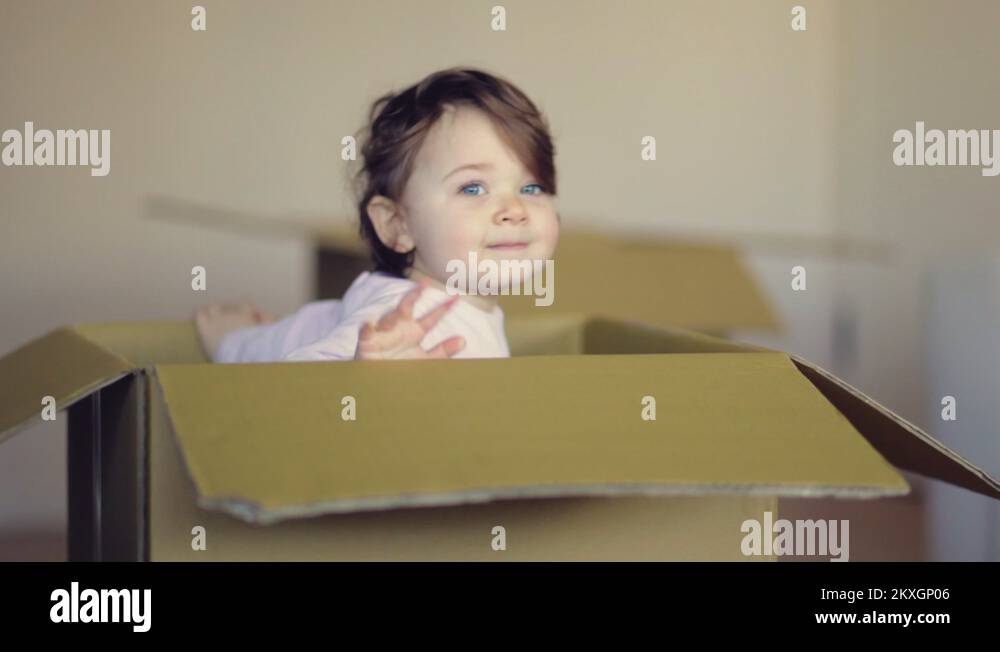 Laughing child girl sitting in cardboard boxe in her new home Stock ...