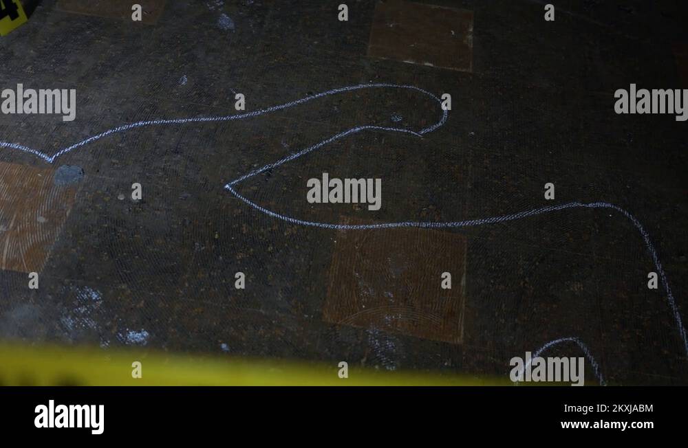 Handheld camera move over yellow police tape over chalk outline at ...