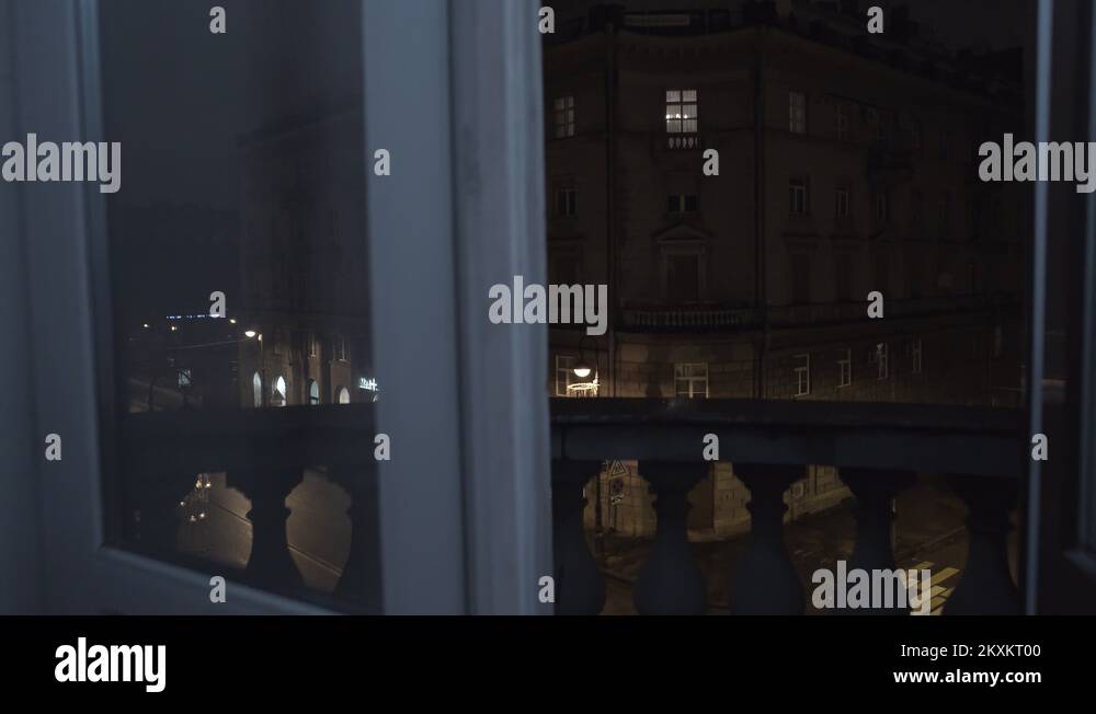 Night city street balcony dolly to room, man writing script on computer ...