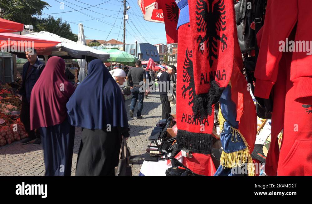 Two Muslim women walk past Albanian shawls on busy market in Pristina ...