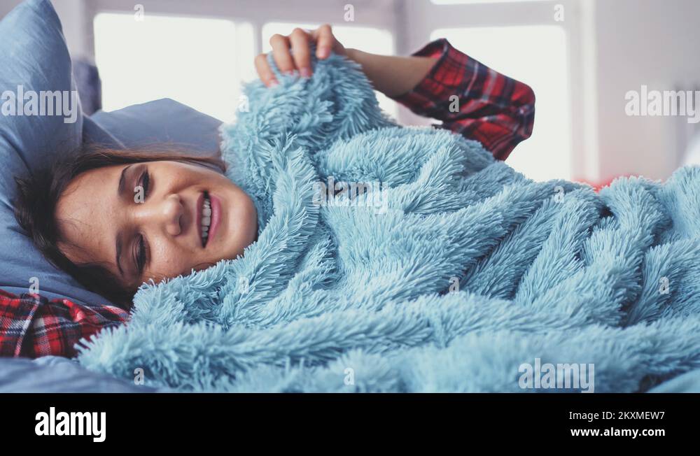 Sleepy young beautiful woman wearing red pajamas lying in bed waking up ...
