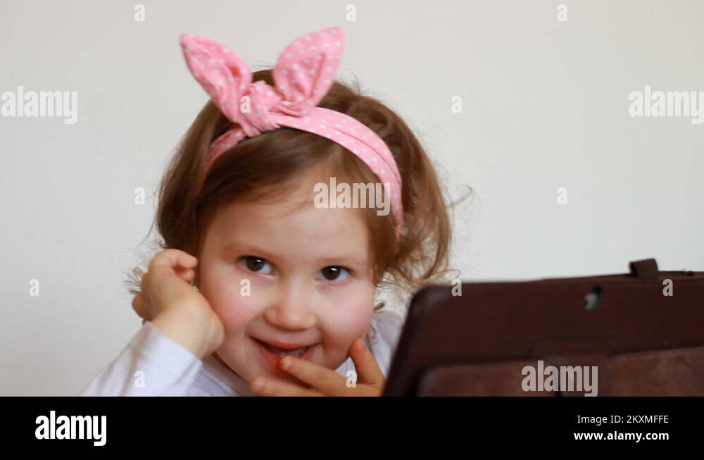 Close-up portrait funny child looks on the computer screen and plays ...