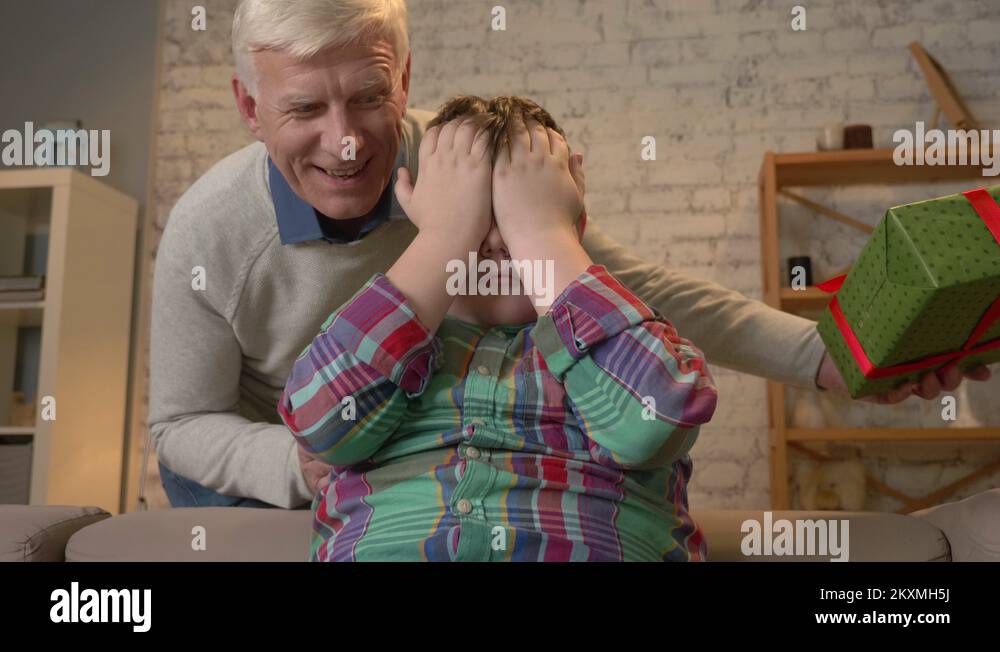 Grandfather gives his grandson a gift. An elderly man gives a gift to a ...