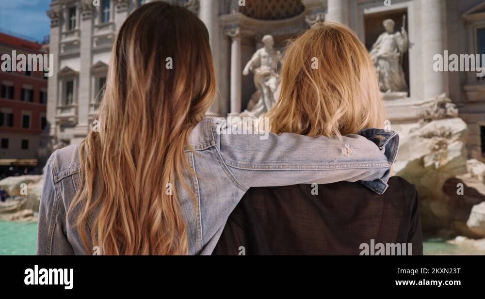 Rearview of two of friendly girls holding each other near Trevi ...