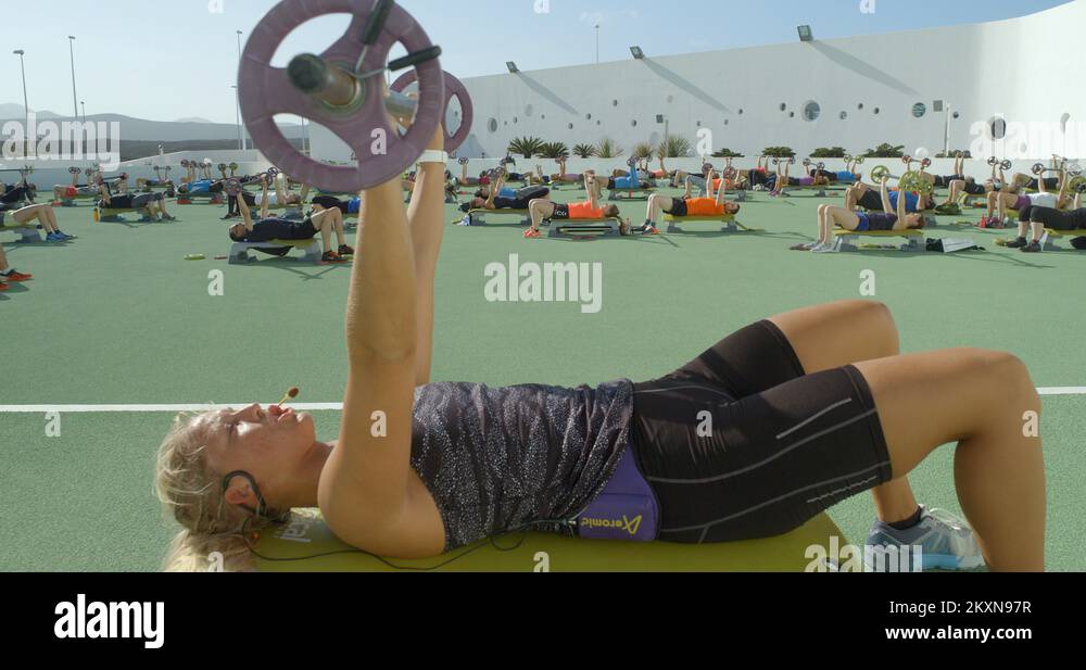 A female aerobics instructor taking a body pump class using weight ...